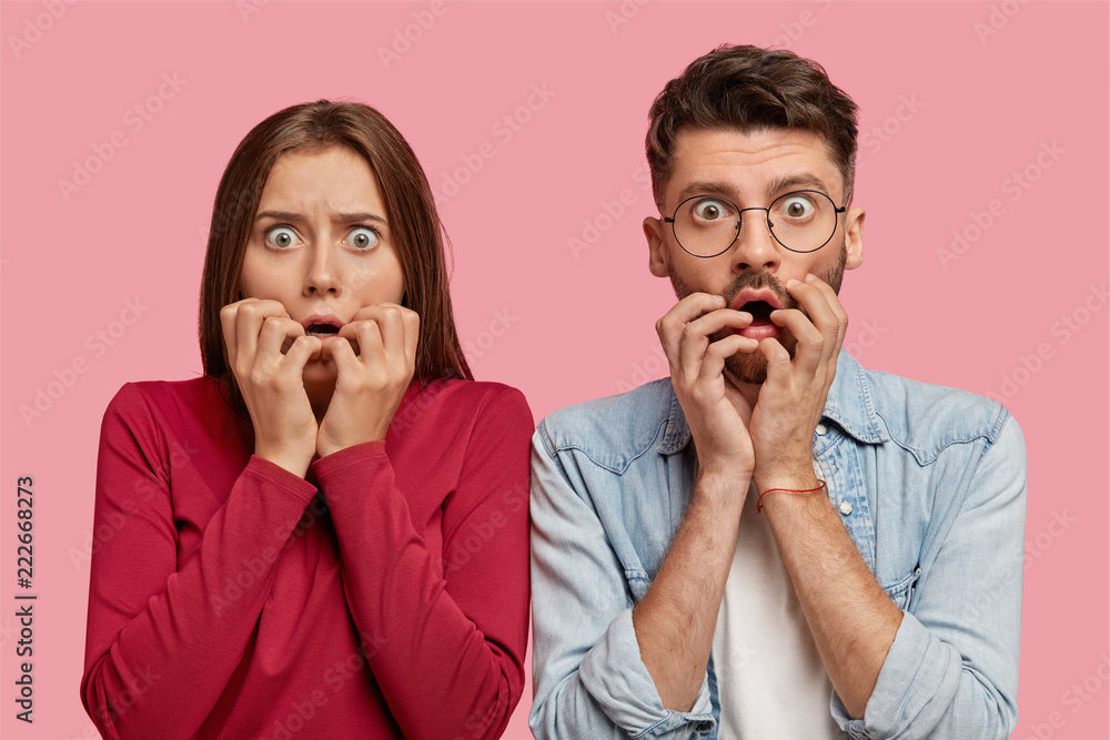 Horizontal shot of terrified young female and male youngsters watch ...