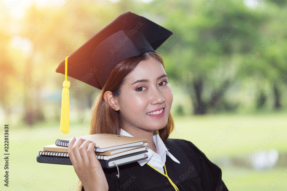 Beautiful Attractive Asian Graduate in cap and gown smile and holding ...