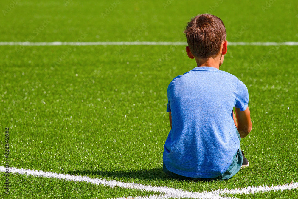 Sad alone boy sitting in soccer field stadium outdoors Stock Photo ...