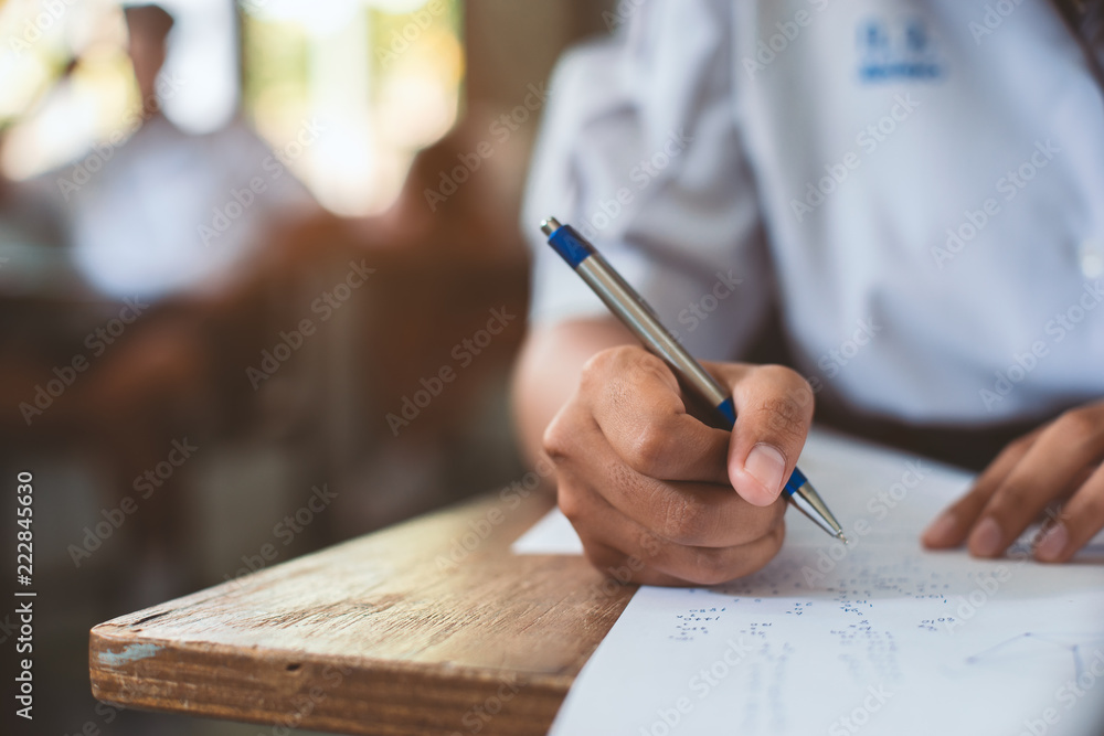 Students writing and reading exam answer sheets exercises in classroom ...