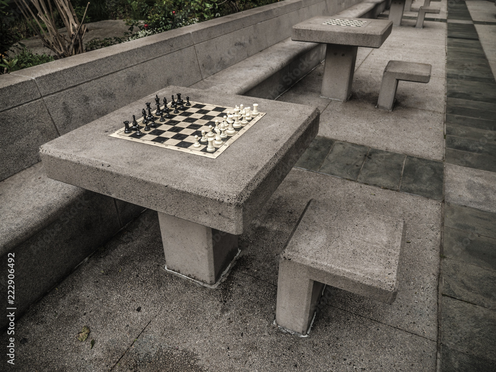 Chess board and pieces on concrete table and benches In a public park ...