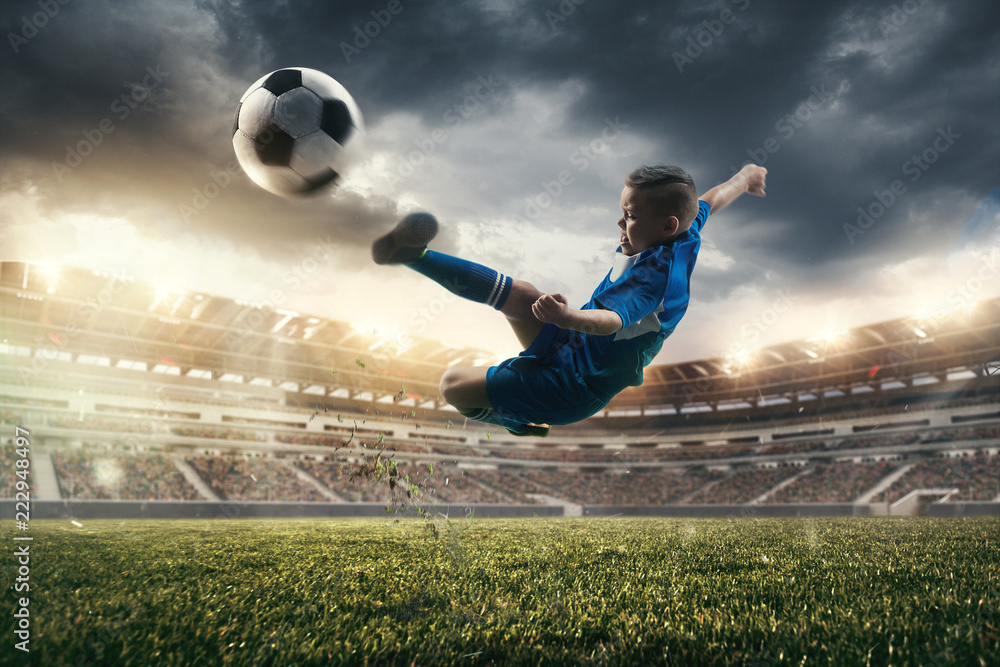 Young boy with soccer ball doing flying kick at stadium. football ...