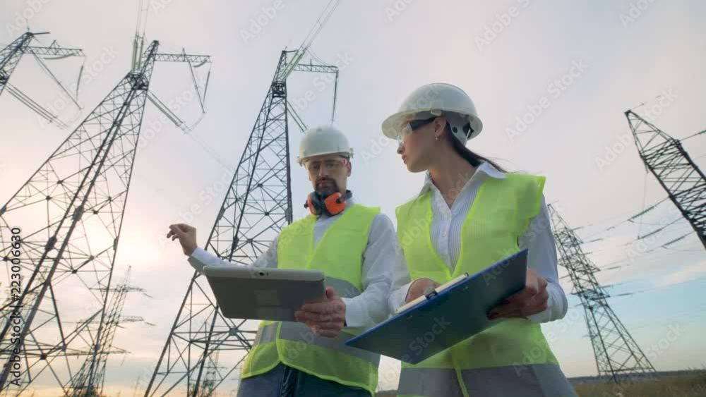 Engineers work with a tablet on power lines. Power lines, power ...