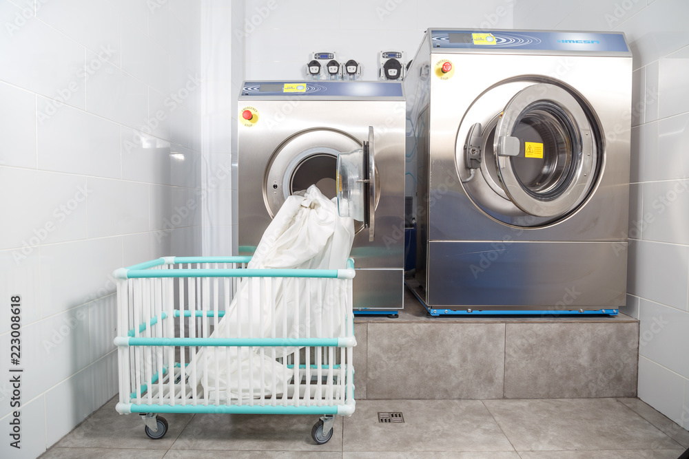 Washing machine overloaded with clothes and empty basket in laundry ...