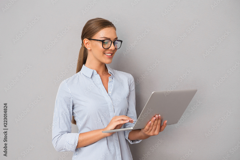Beautiful smiling business woman standing over grey wall background ...