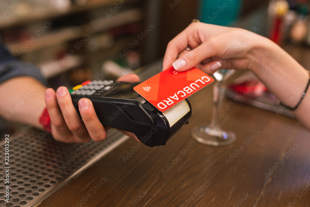 Club card. Regular client using club card while paying for the bill in ...