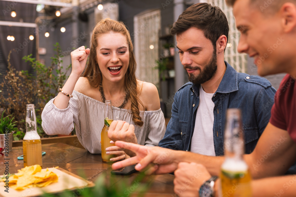 One two three. Young friendly people sitting in the bar and smiling ...