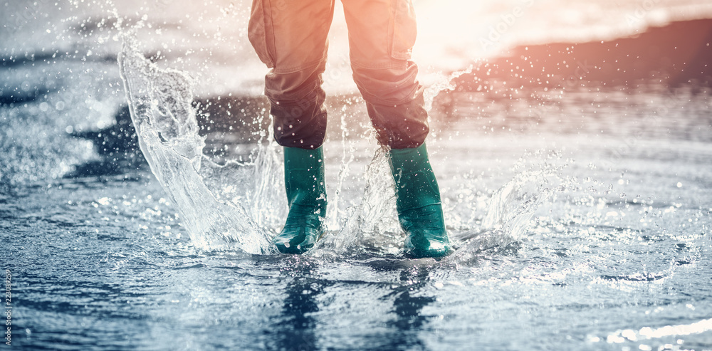 Child walking in wellies in puddle on rainy weather. Boy under rain in ...