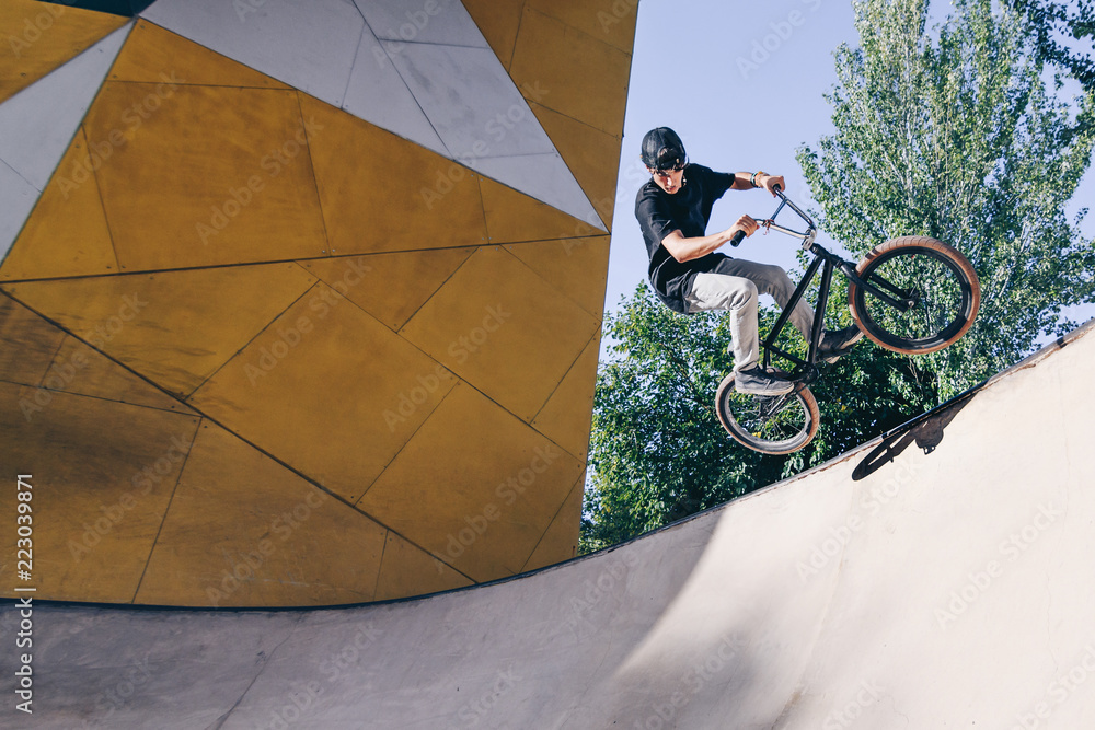 BMX rider makes a TAilwhip trick. Young man doing tricks in the air on ...