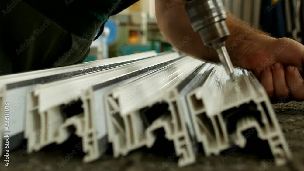 Production of pvc windows, the worker screws a metal profile to the ...