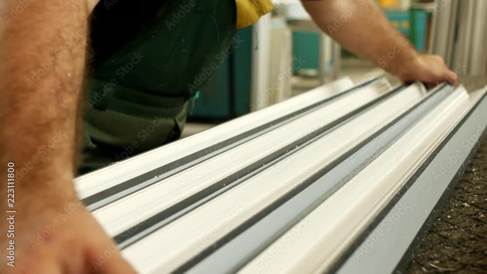 Production of pvc windows, male worker punctures the details of a pvc ...