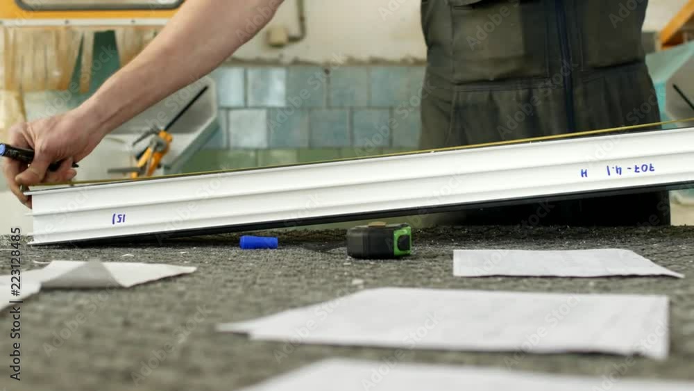 Production and manufacturing of pvc windows, a male worker is measuring ...