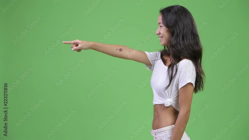 Profile view of young happy beautiful multi-ethnic woman pointing ...