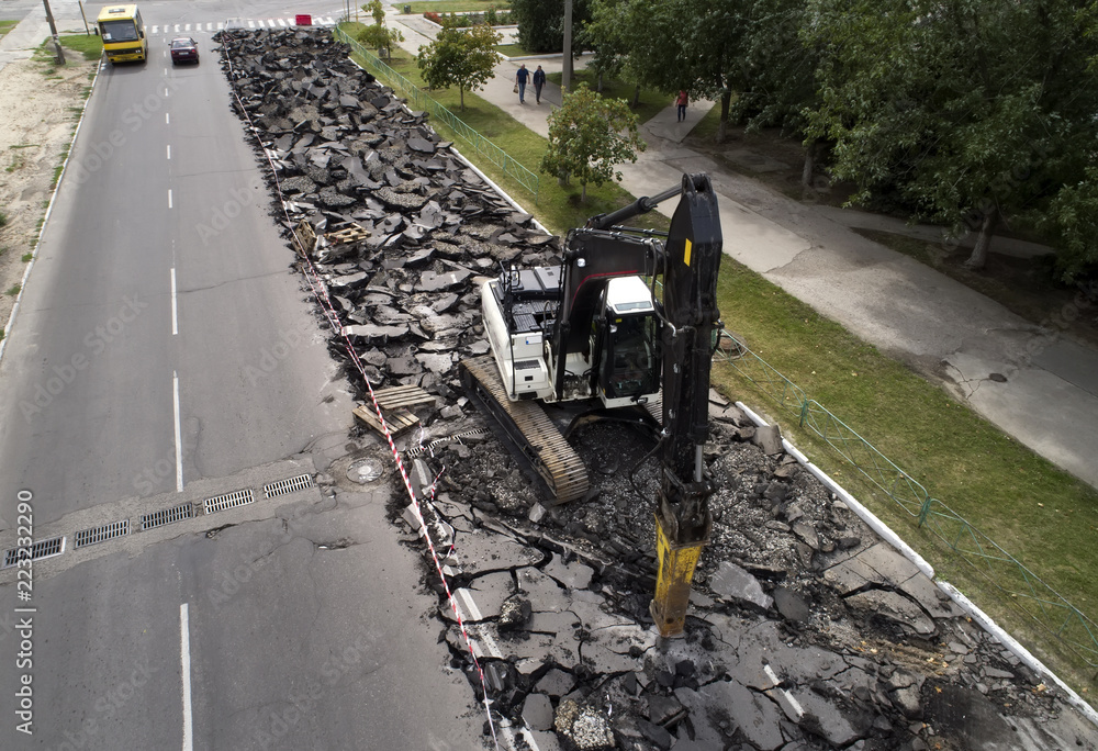 Excavator breaking concrete road surface with hydrohammer drill at ...