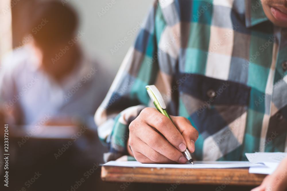 Students writing and reading exam answer sheets exercises in classroom ...