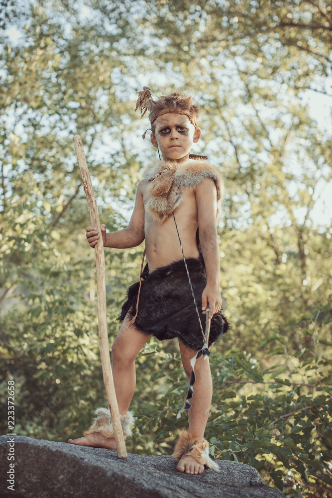 Caveman, manly boy with staff and bow hunting. Prehistoric tribal boy ...