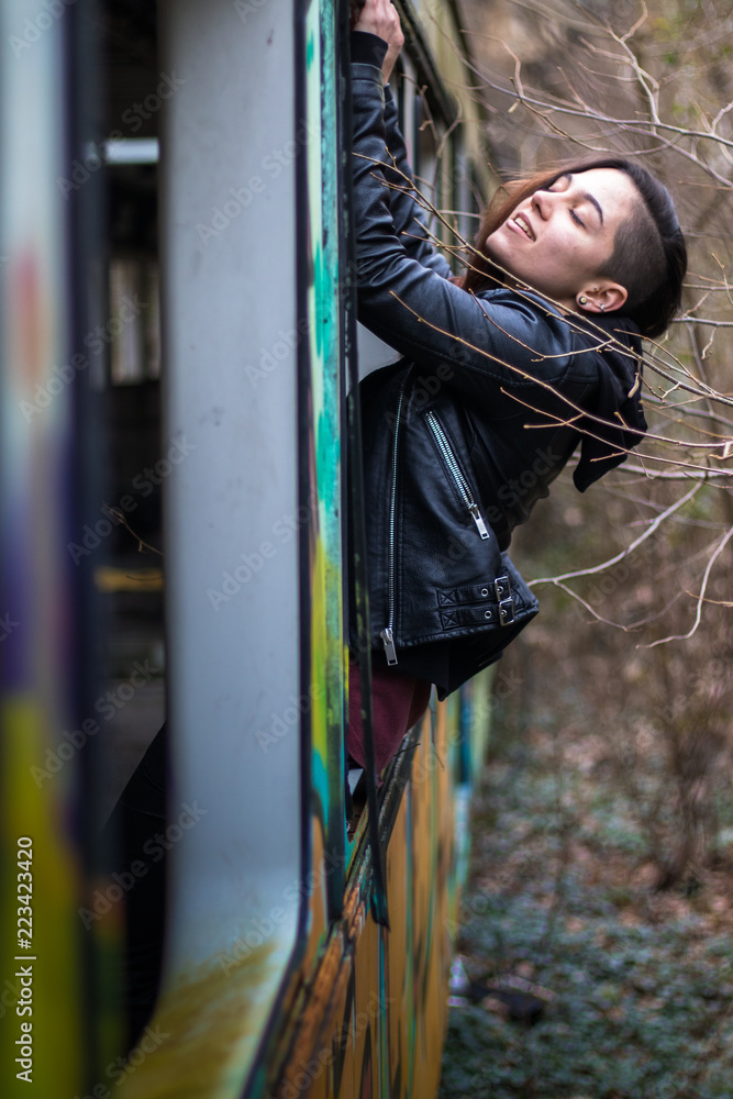 Young brunette woman hanging out of an abandoned train window in the ...