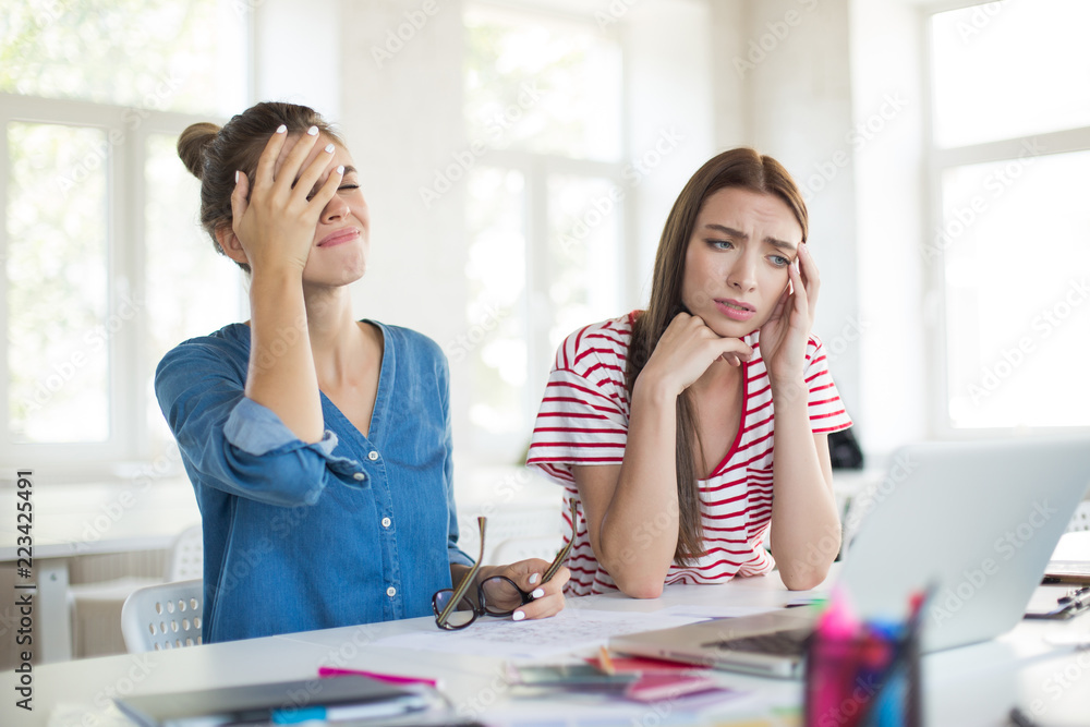 Girl in denim shirt with eyeglasses sadly covering face with hand while ...