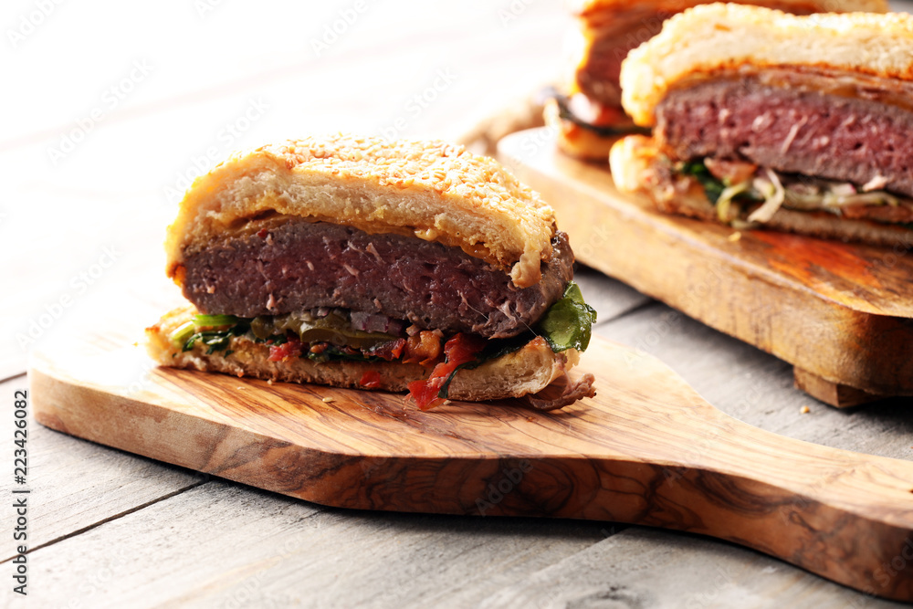 Cut in half angus burger on grain bun with tomato relish, lettuce and ...