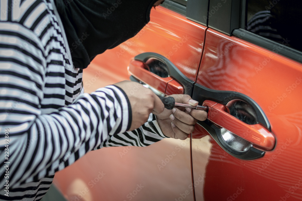Robber and the car thief in a mask opens the door of the car and ...