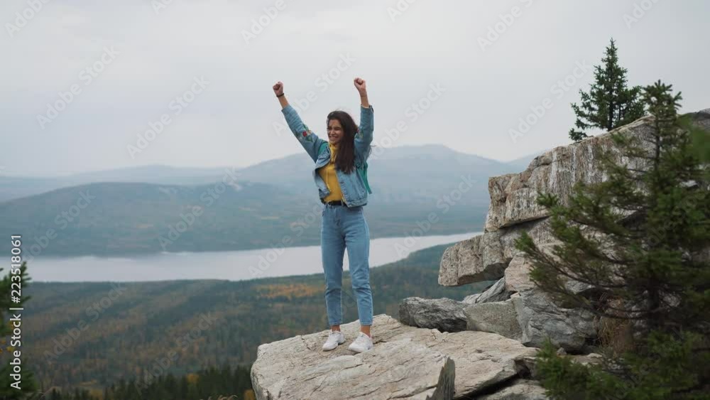 Attractive woman standing on a mountain peak with her long hair blowing ...