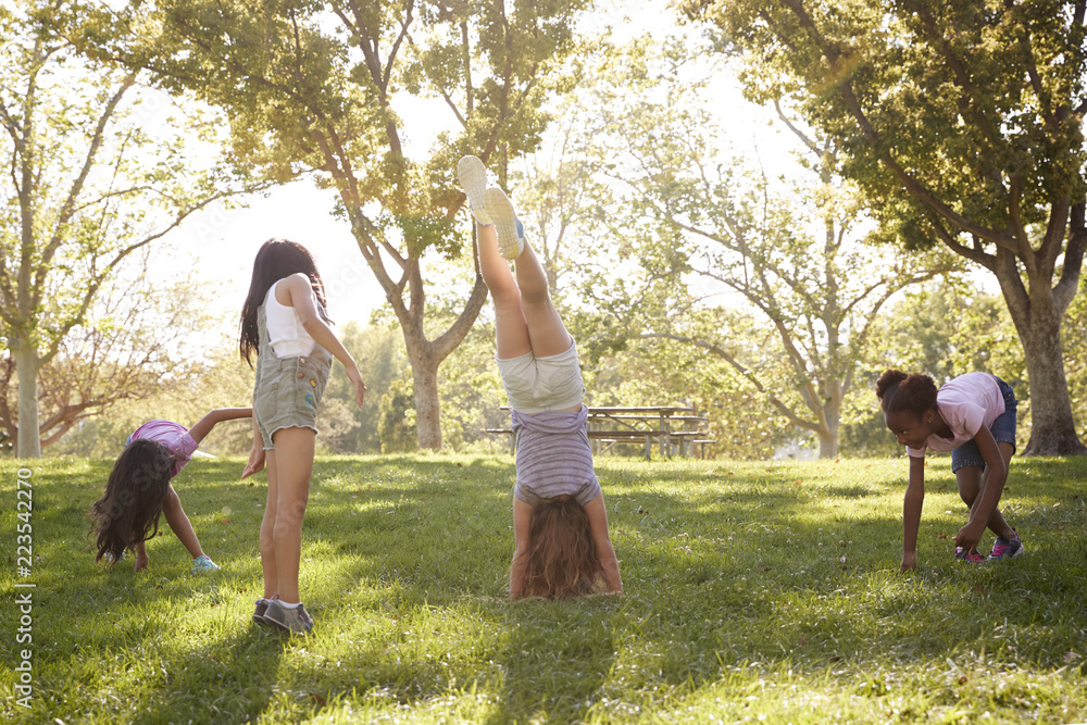 Four young girlfriends doing handstands together in a park Stock Photo ...