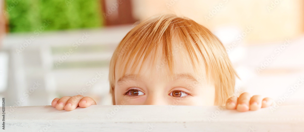 Cute little boy hiding behind a bench outdoors. Child having fun ...