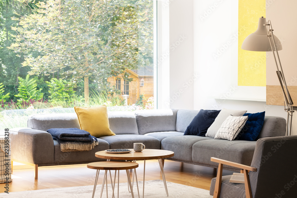 Tables next to armchair and grey corner sofa in living room interior ...