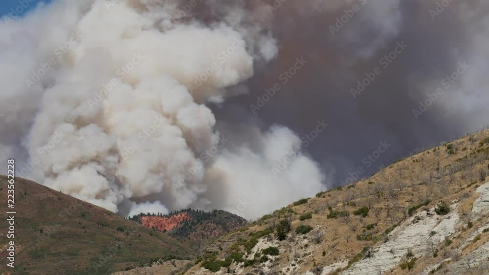 Zoom in-Clouds of billowing smoke rise-over red rock cliffs-Pole Creek ...