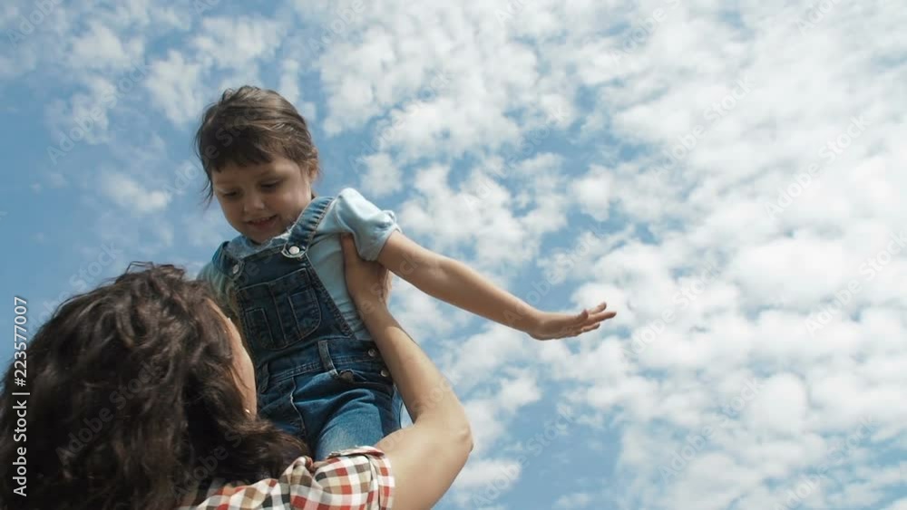 The mother plays with the child. The woman throws the child up ...