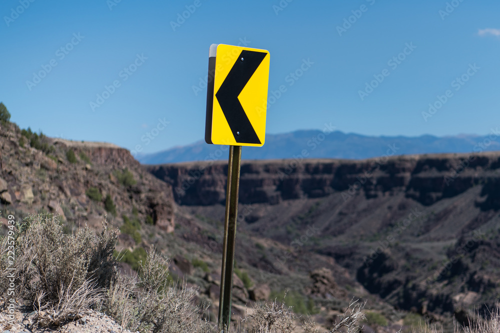 Left turn arrow road sign at a switchback on a road at the canyon rim ...