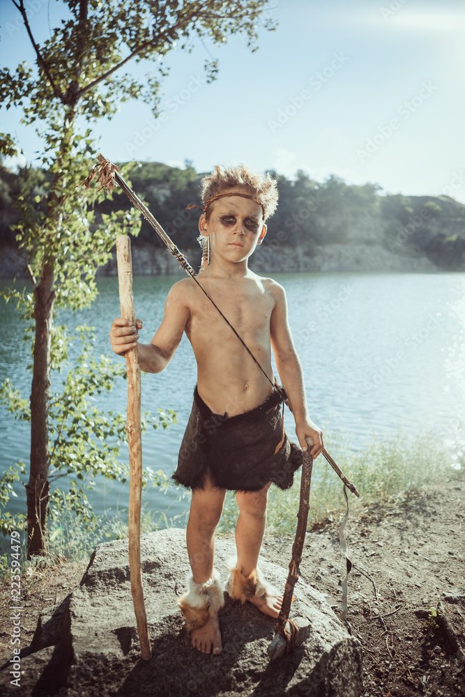 Caveman, manly boy with stone axe and bow hunting near river ...