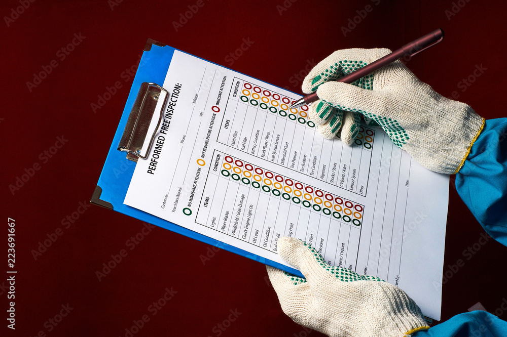 Mechanic writes in the performed free inspection form on a red velvet ...