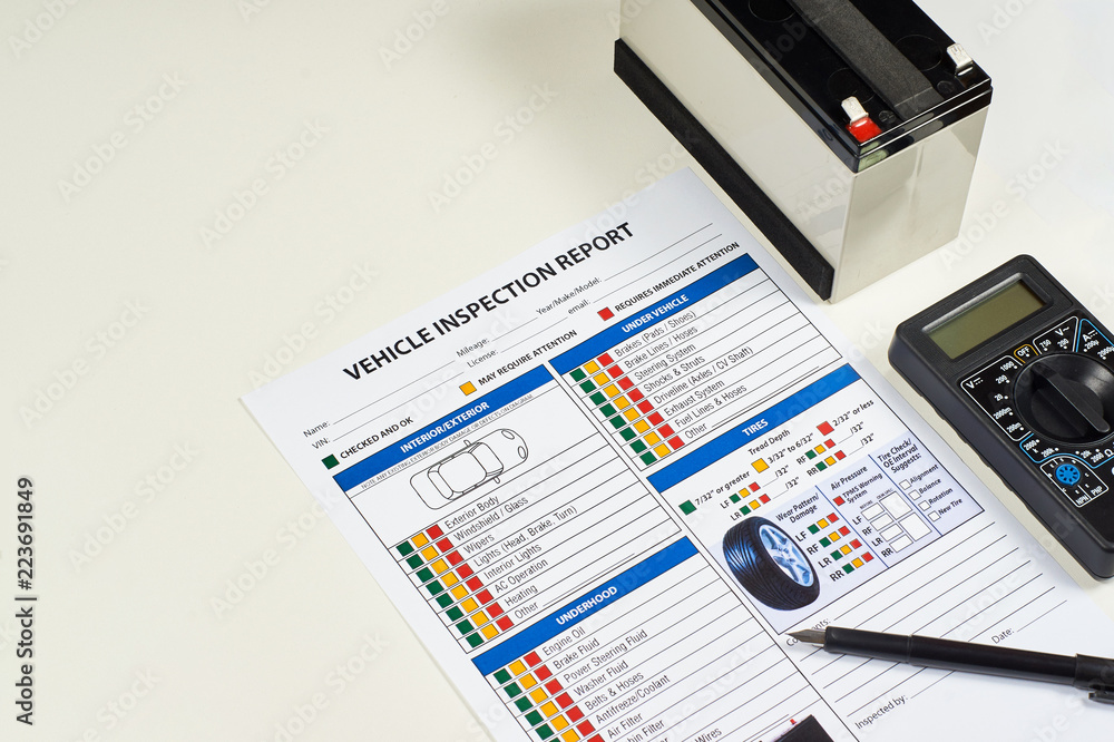 Vehicle inspection report form with multimeter, pen and battery on ...