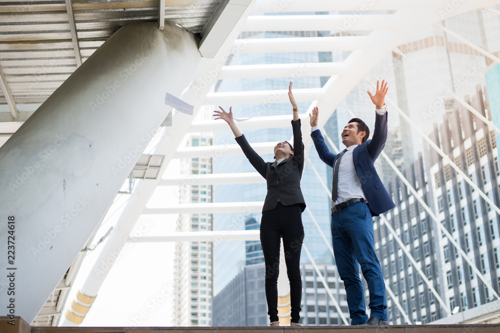 Asian businessman and businesswoman throwing paper in the air and ...