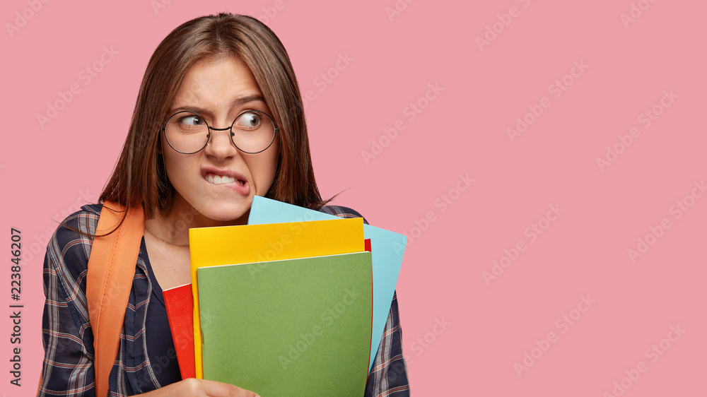 Worried puzzled student bites lower lips, looks stressfully and ...