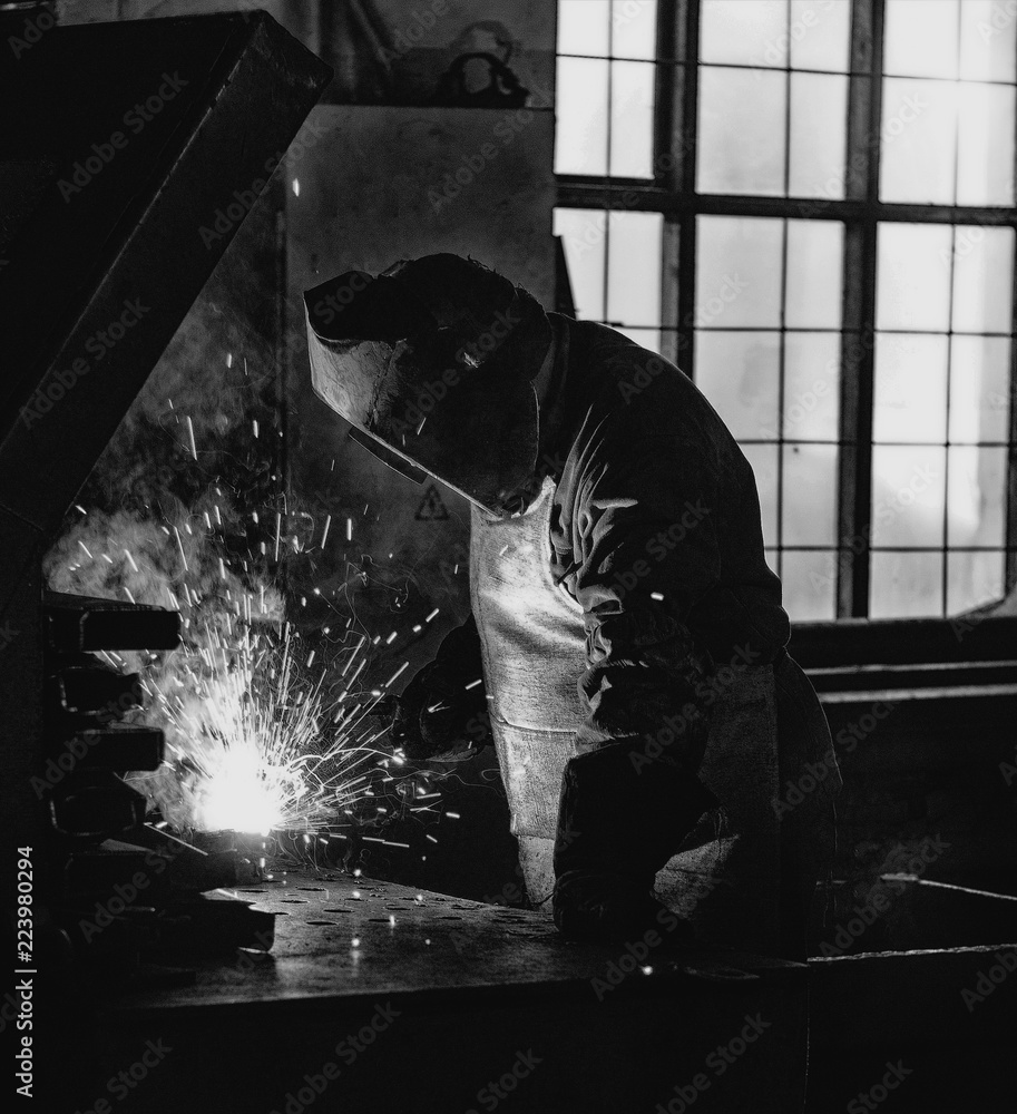 Welder at the factory in a welding mask welds metal parts, welding and ...