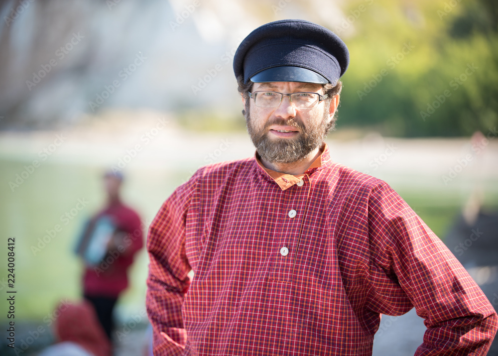 A man in a Russian-folk costume stands on a background of water and ...