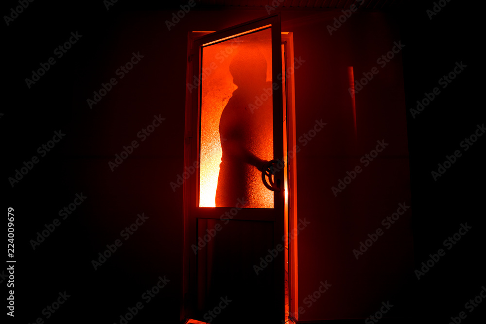 Silhouette of an unknown shadow figure on a door through a closed glass ...