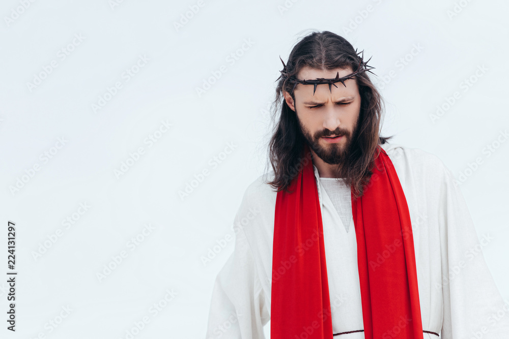 Jesus in robe, red sash and crown of thorns looking down against light ...