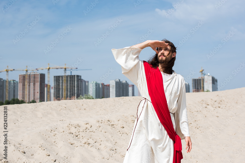Jesus in robe, red sash and crown of thorns standing on sand and ...