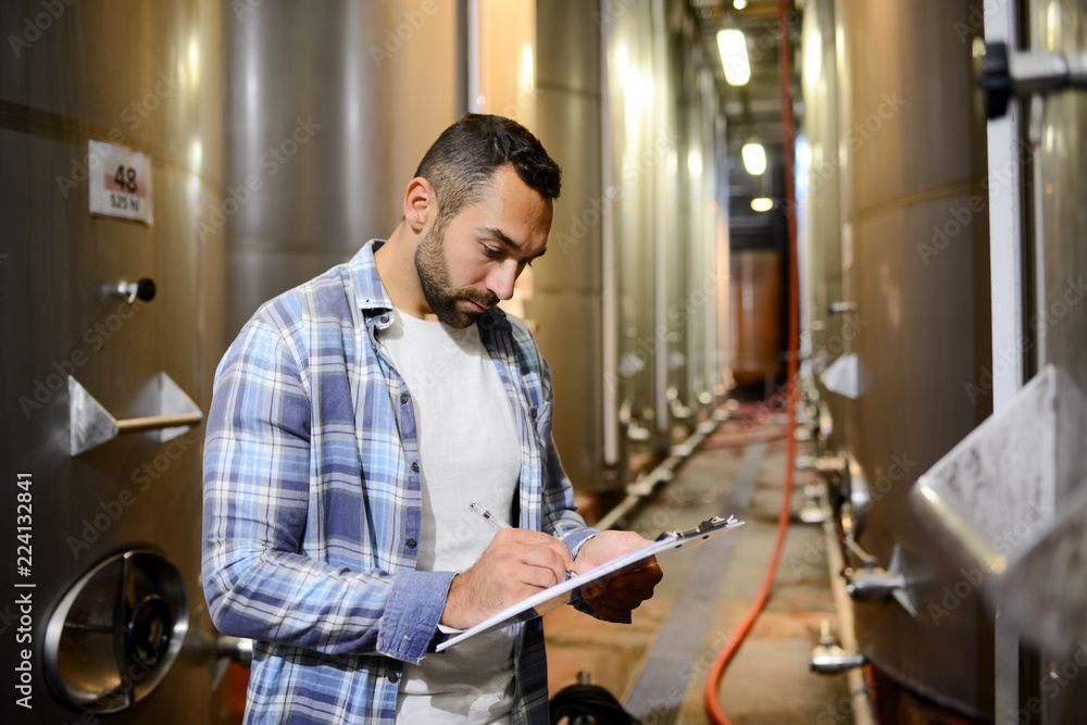 handsome man winemaker in a winery wine cellar during harvest season ...