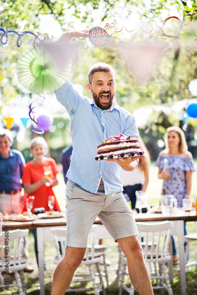 Man jumping with a cake on a family celebration or a garden party ...