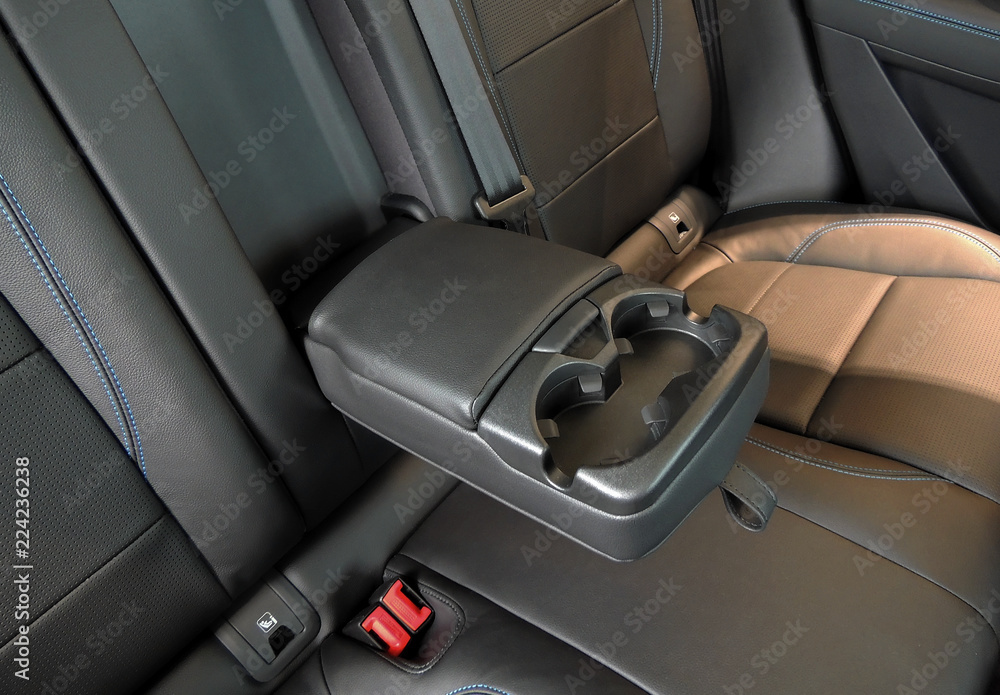 Leather trimmed folding armrest with cup holders in rear seats inside a ...