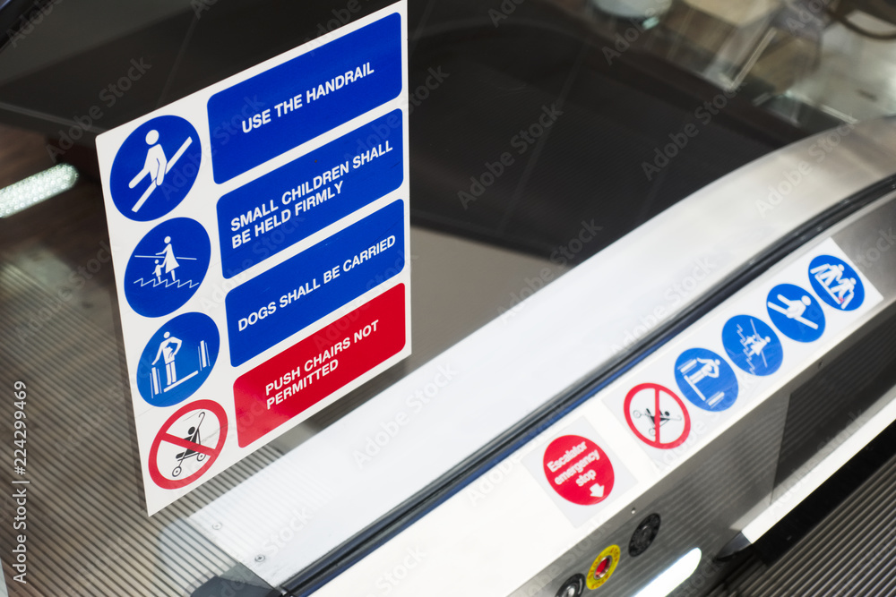 Escalator safety sign symbols close up and text on glass at top of ...