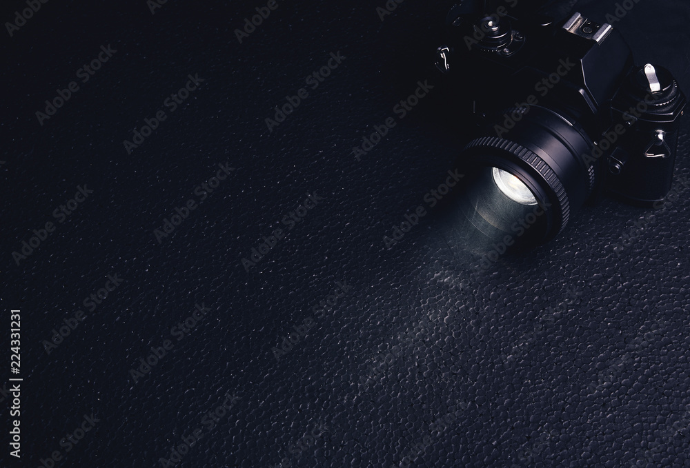 old camera with a ray of light from the lens in the smoke on a black ...