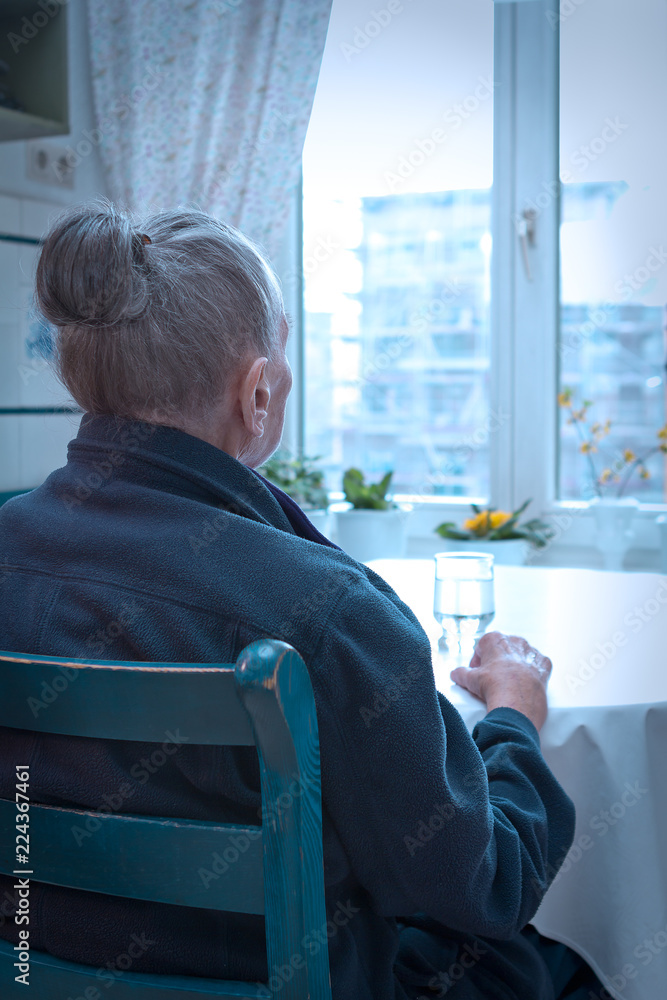 Loneliness concept, old-age depression: old woman sitting alone at her ...