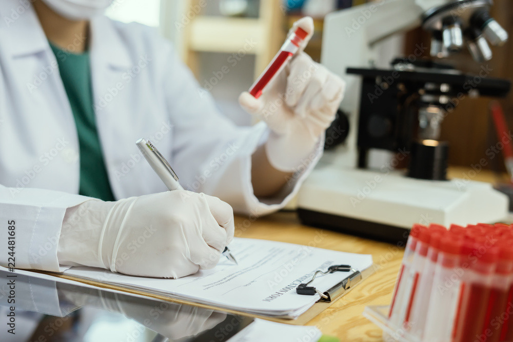 hands a medical doctor holding blood-sample and making notes writing on ...