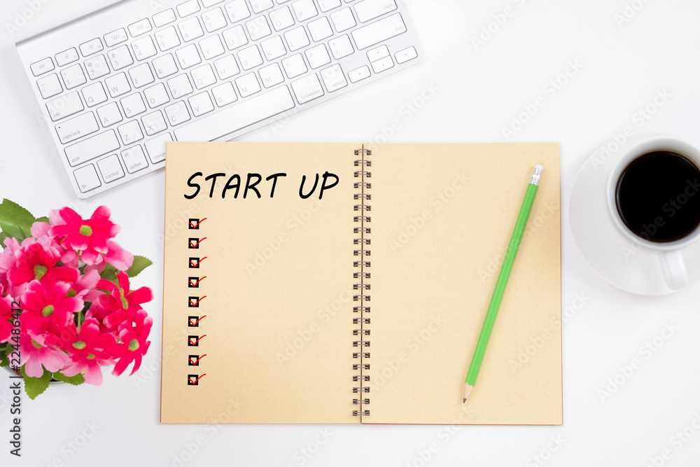 Note book with start up word and check marks, keyboard, red flower ...