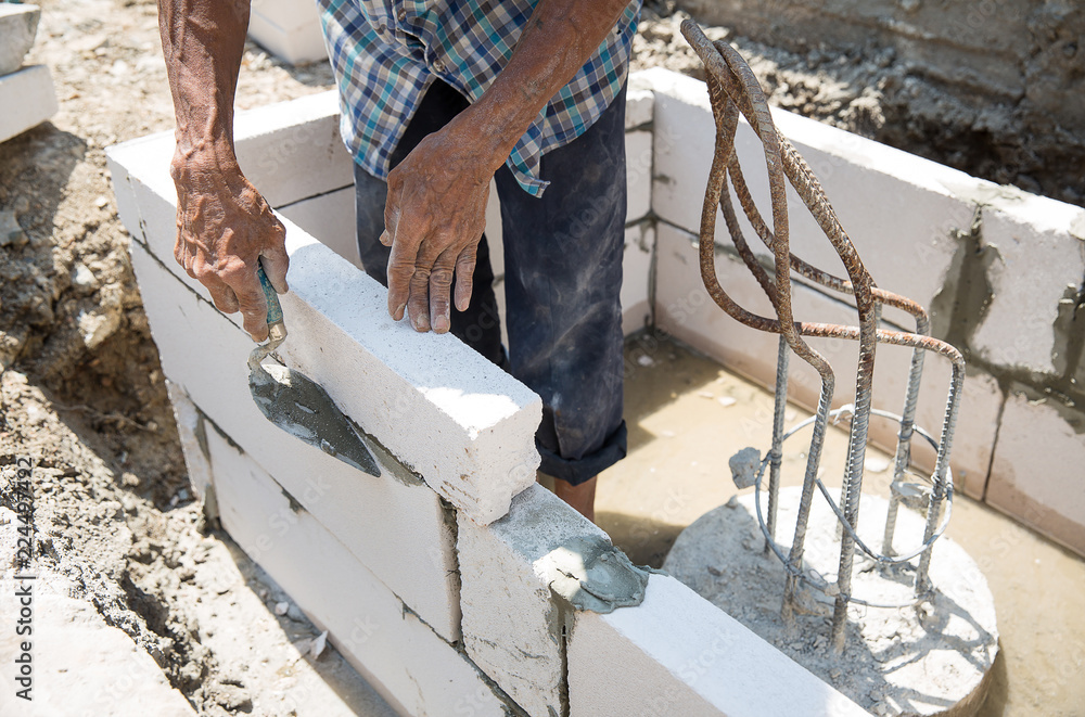 worker is building brick layer to wall, bricklaying and mansory in ...